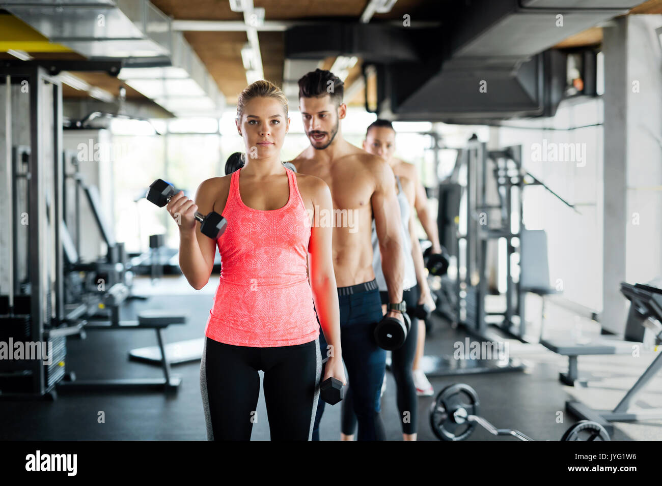 Personal trainer helping young woman with exercises for biceps Stock ...