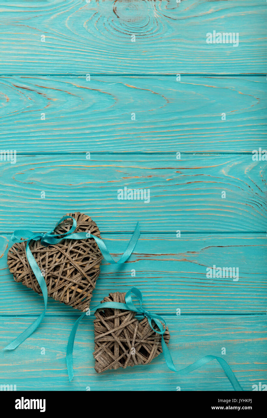 Decorative wicker hearts of gray color with a blue ribbon on a wooden ...