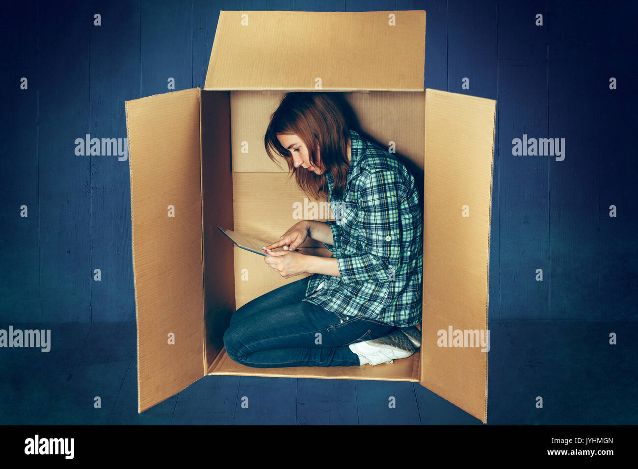 Introvert concept. Woman sitting inside box and working with laptop ...