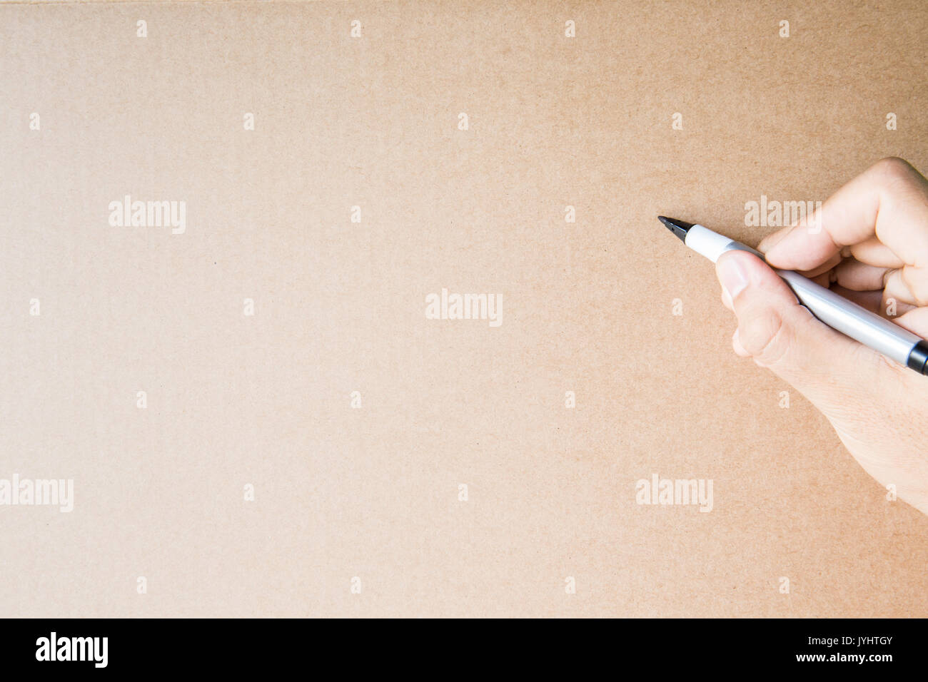 hand holding pen with brown paper background Stock Photo - Alamy