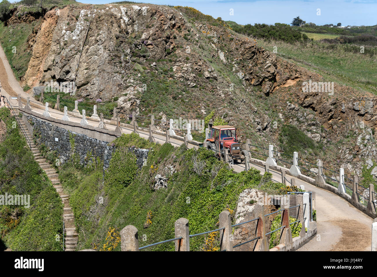 A tractor crossing La Coupee, a narrow causeway with a 300 feet drop on ...