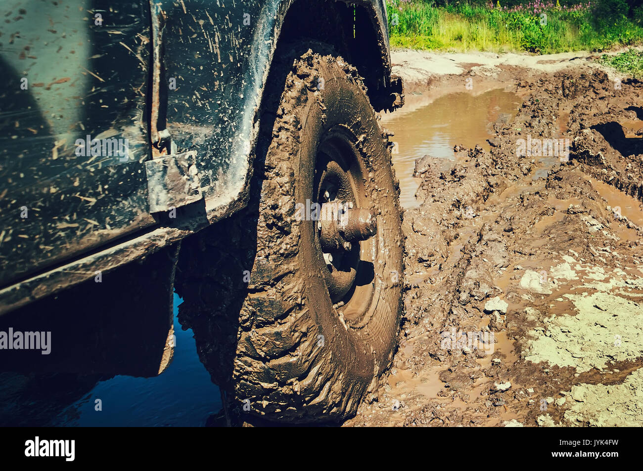 truck on a bad road. The wheel of the SUV in the mud in the foreground ...