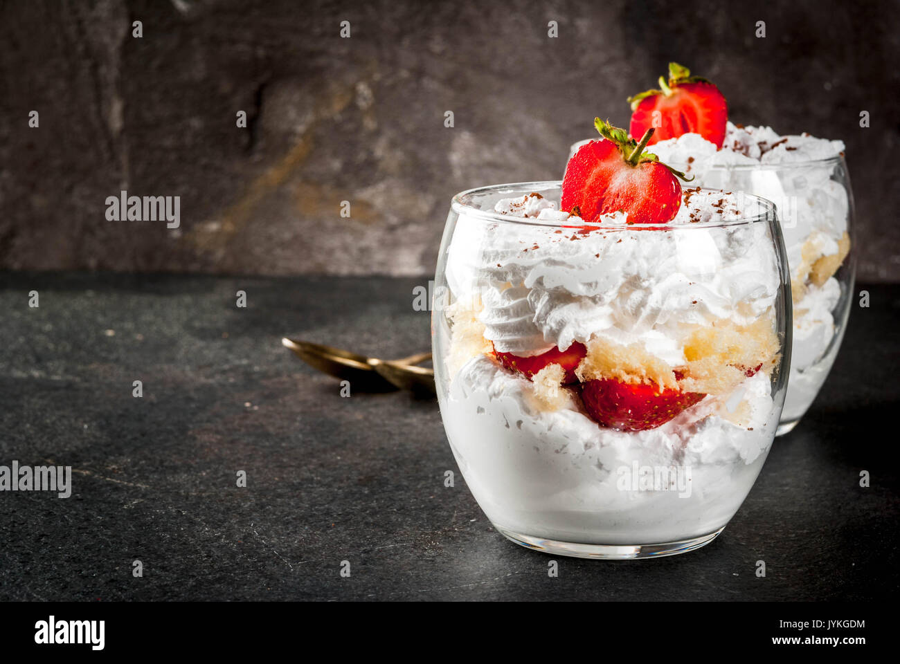 Layered dessert parfait in a glass with strawberries, sponge cake and ...