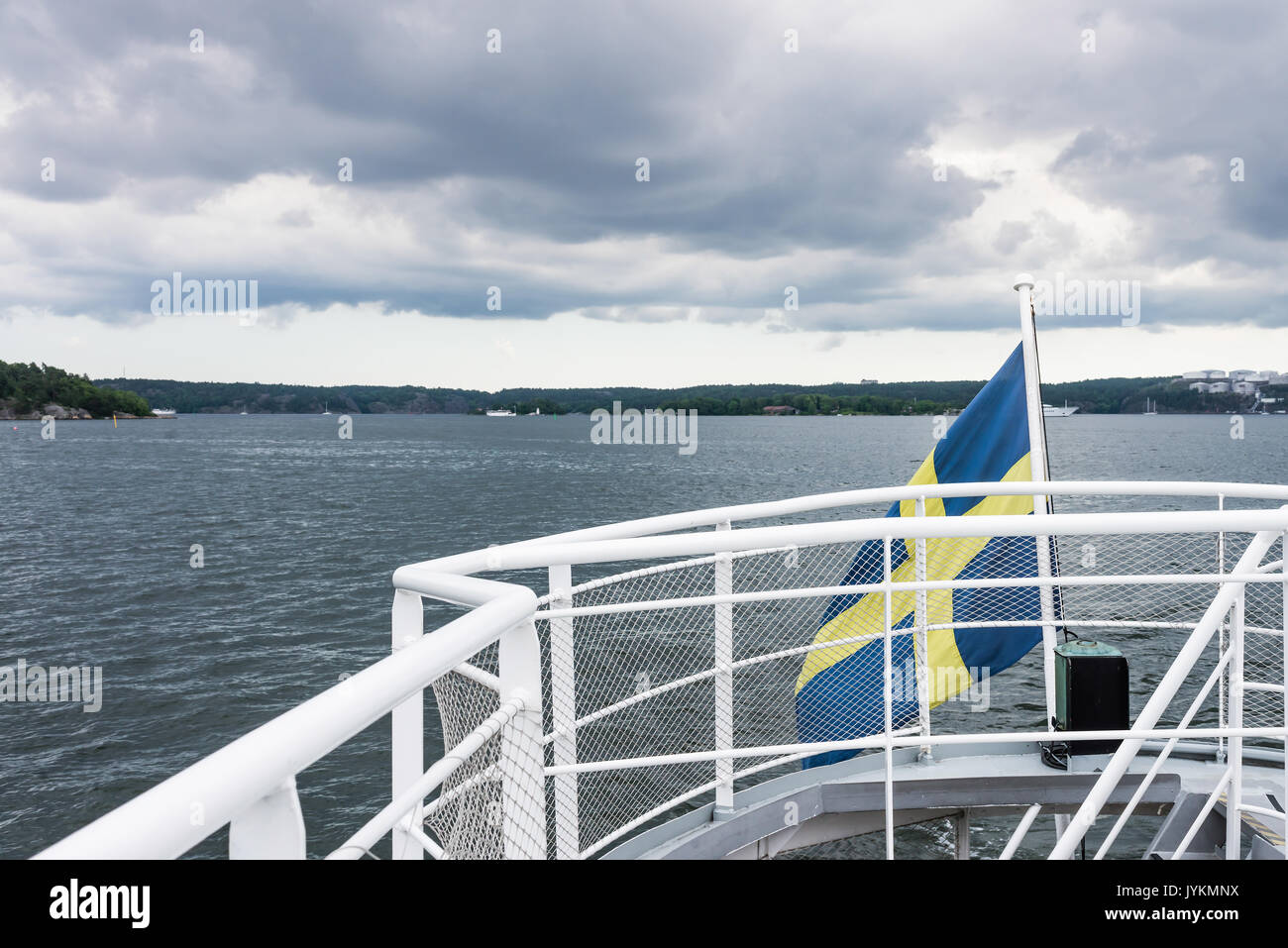 Swedish flag waving on a boat with a view over forests and water in the ...