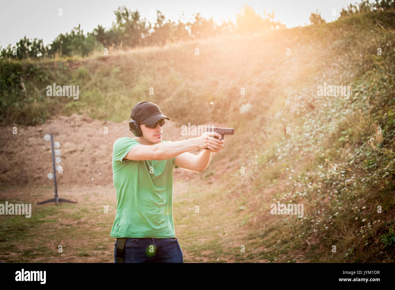 Handsome and muscular caucasian handsome guy firing from fire gun glock ...