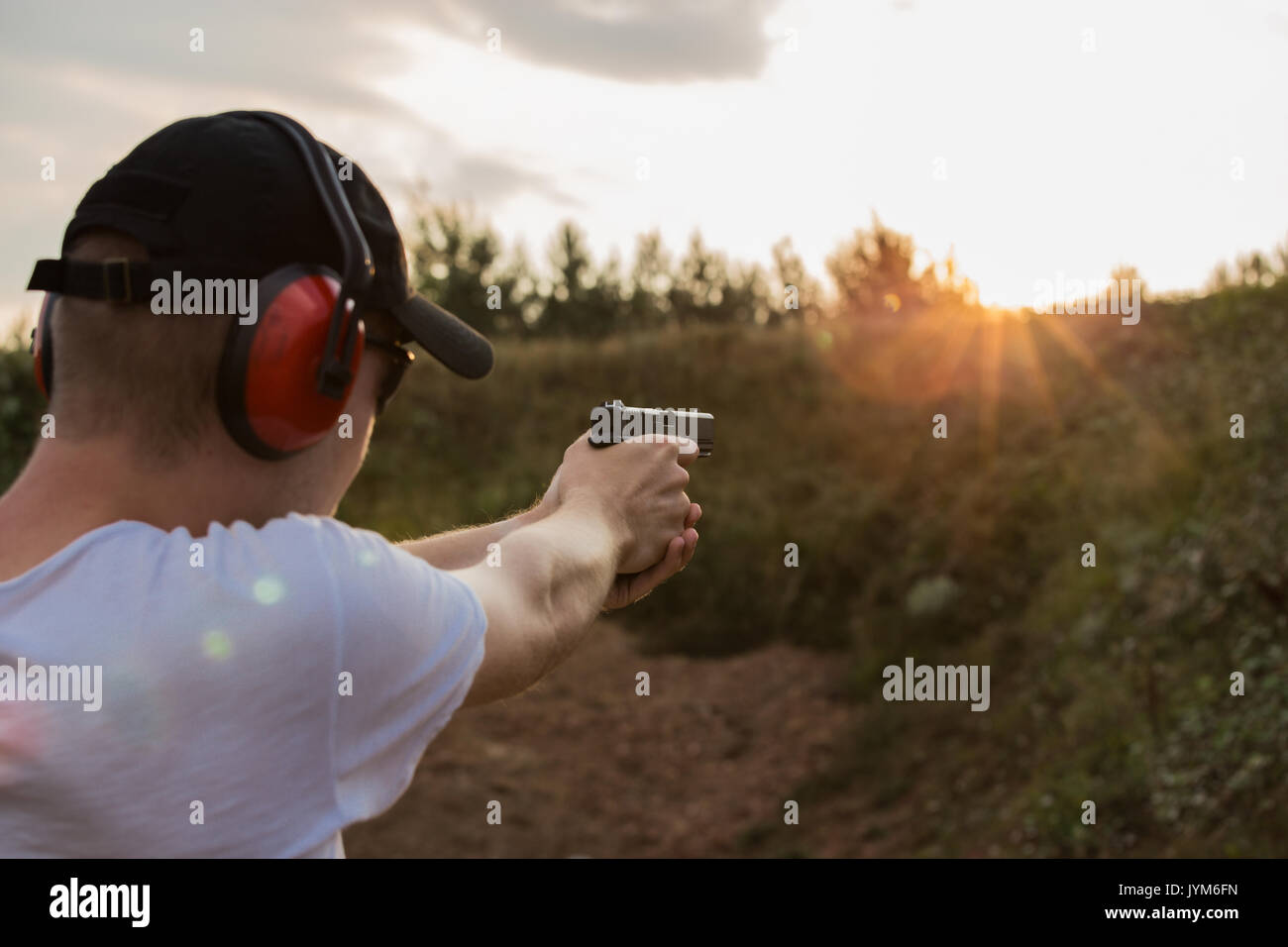 Handsome young blonde guy shooting at the target with gun glock pistol ...