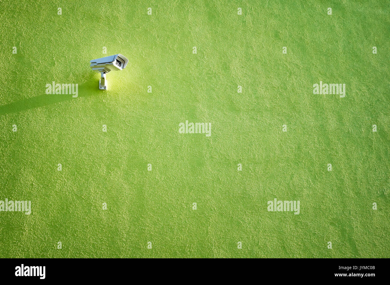 Closed circuit television (CCTV) camera on a green building wall, space ...