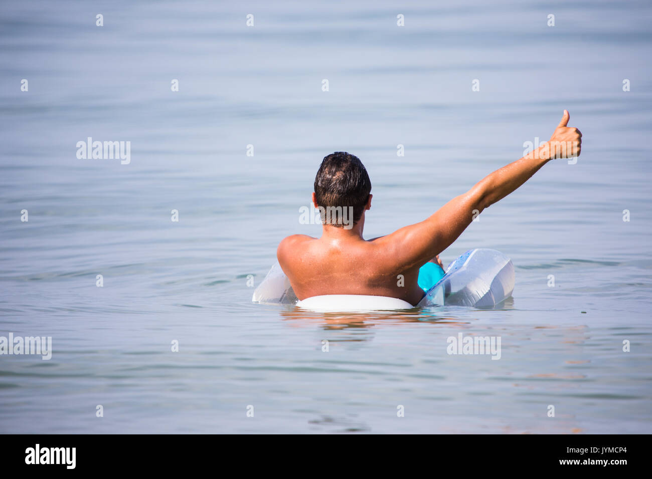Man sitting in inflatable ring on sea hi-res stock photography and ...