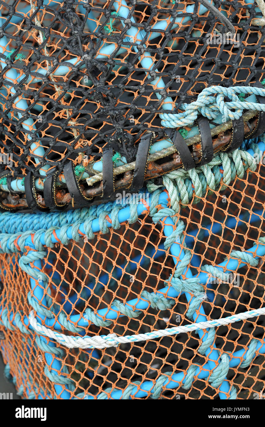 two lobster pots in a stack on a quayside or harbour wall with nets and ...