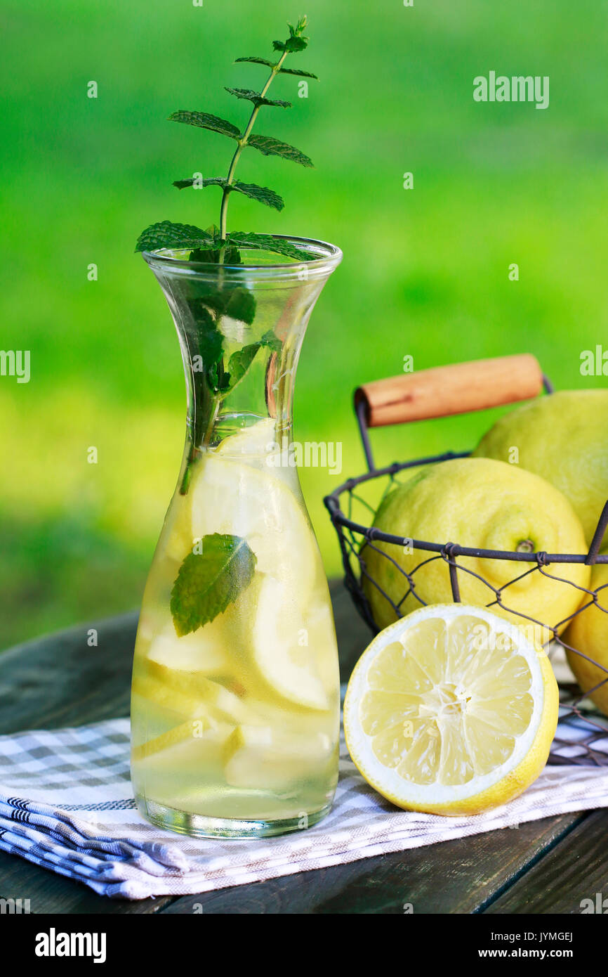 Lemonade in the bottle and fresh fruits in wire basket. Summer garden ...