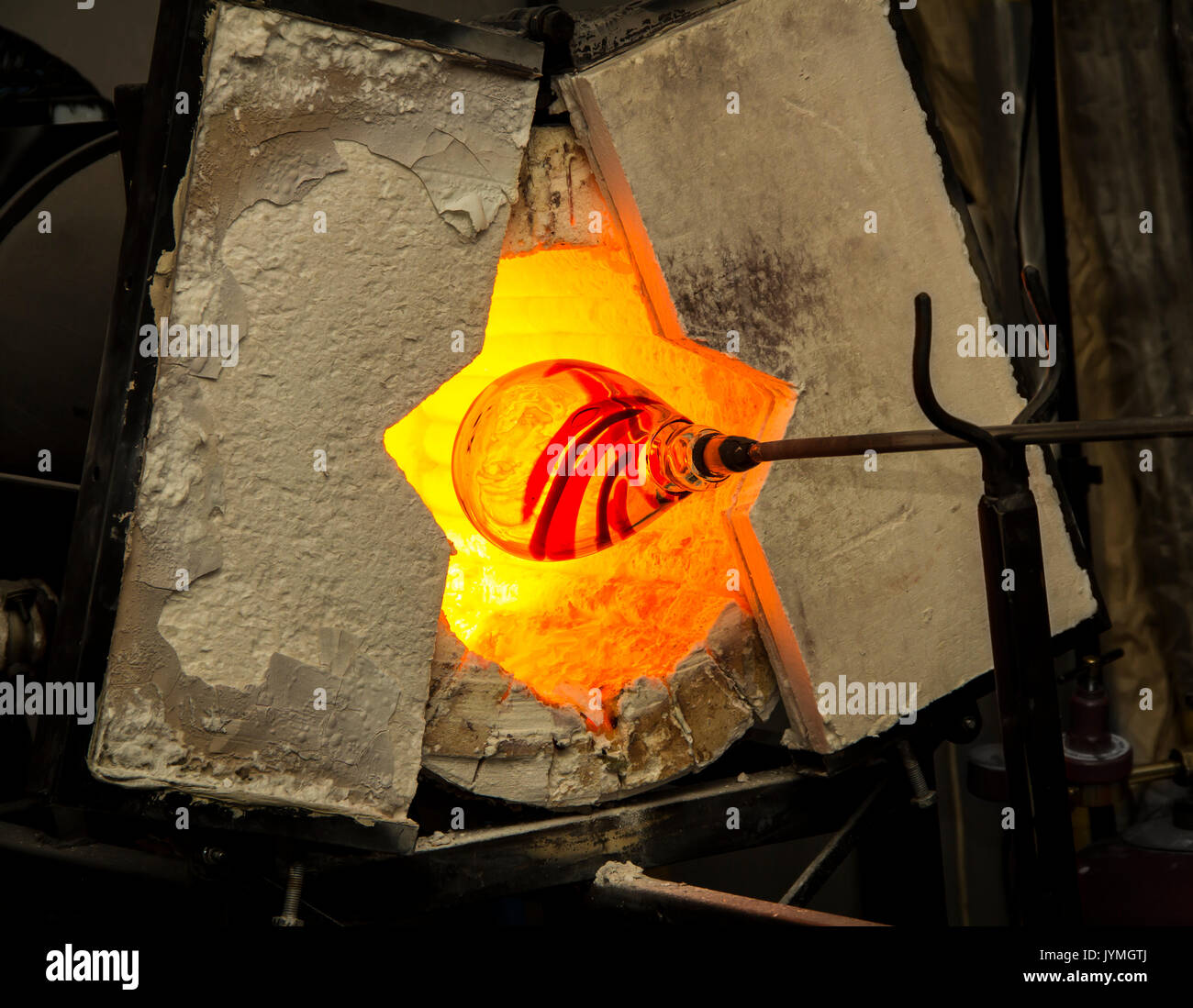 Handmade figure of melted glass, a glass blower working molten glass on ...