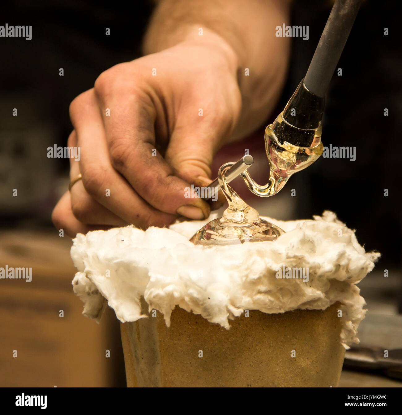 Handmade figure of melted glass, a glass blower working molten glass on ...