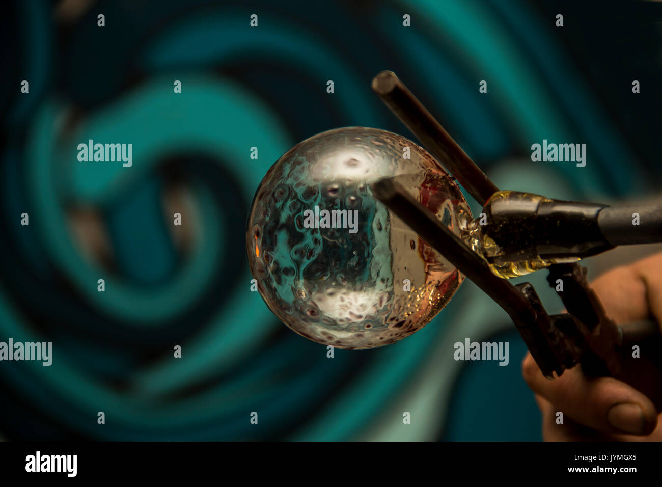 Handmade figure of melted glass, a glass blower working molten glass on ...