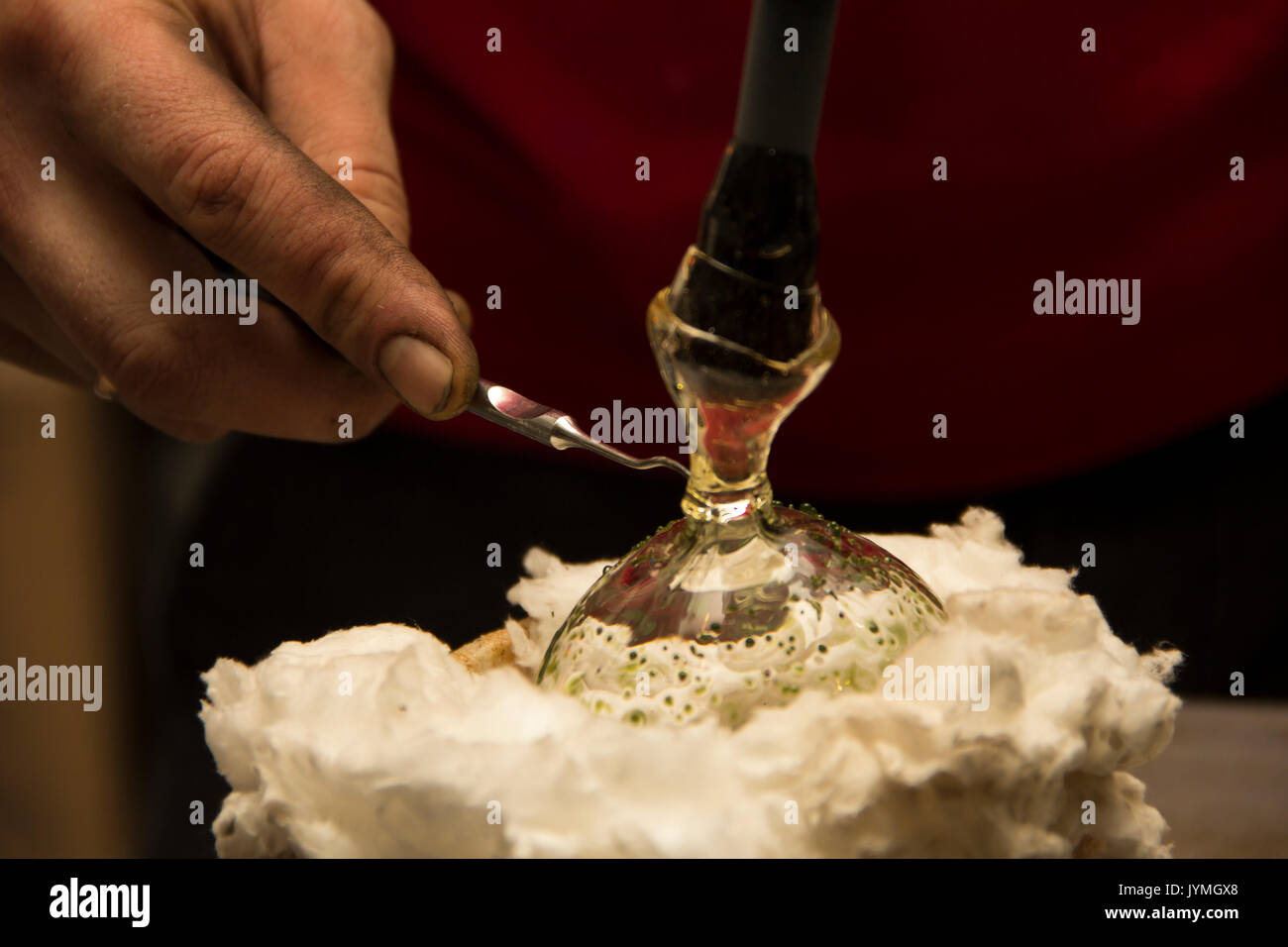 Handmade figure of melted glass, a glass blower working molten glass on ...