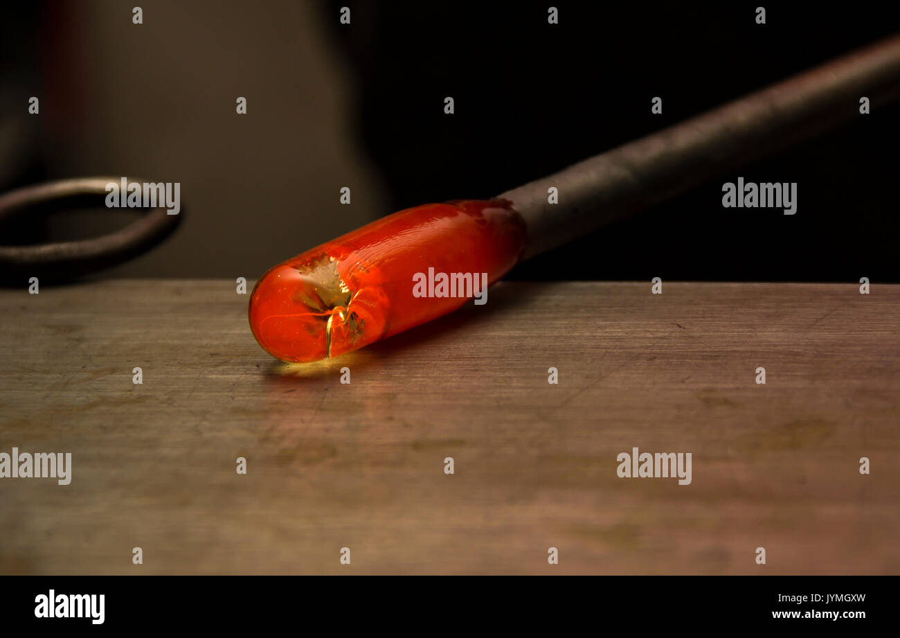 Handmade figure of melted glass, a glass blower working molten glass on ...