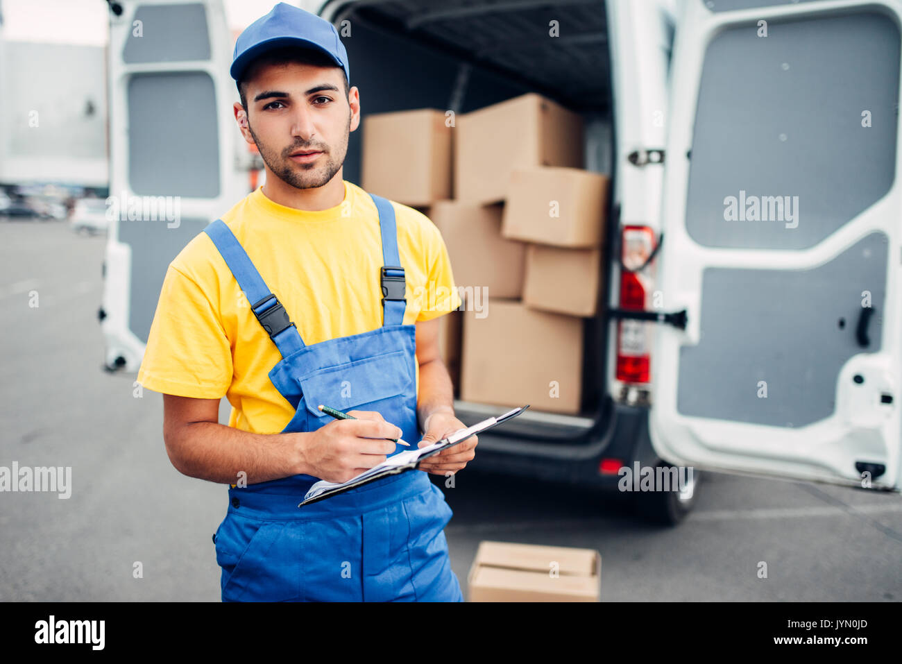 Cargo delivery service, male courier in uniform and truck with ...
