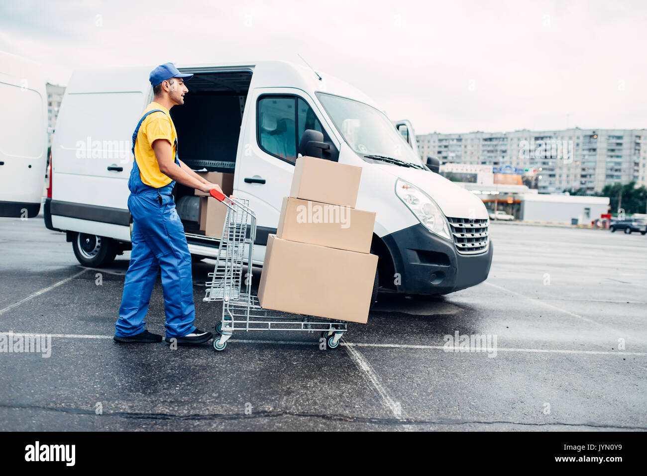 Male courier with parcel trolley against truck with carton boxes ...