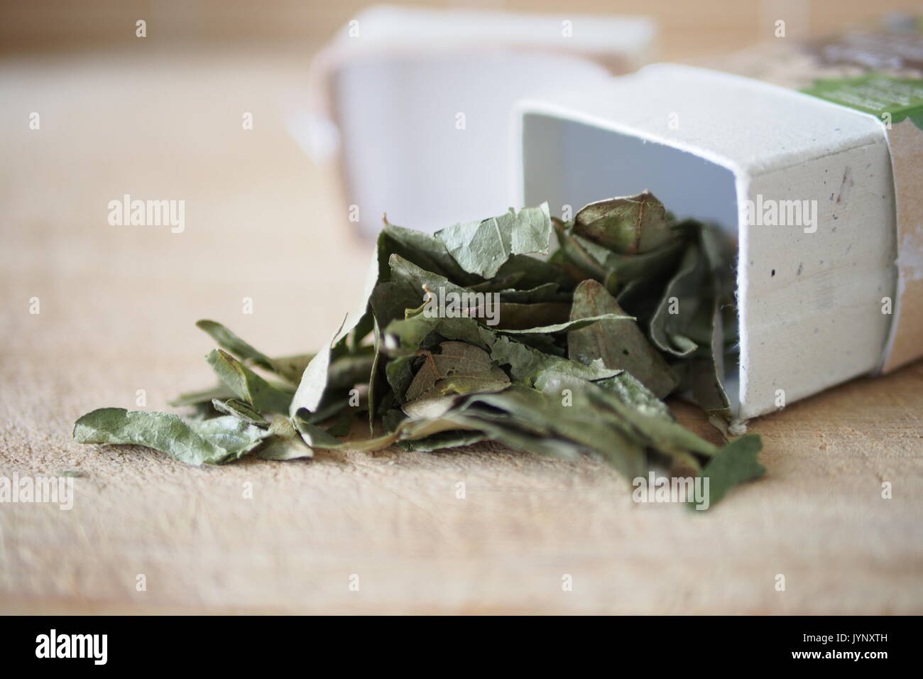 Loose dried curry leaves spilling from a cardboard container onto a ...