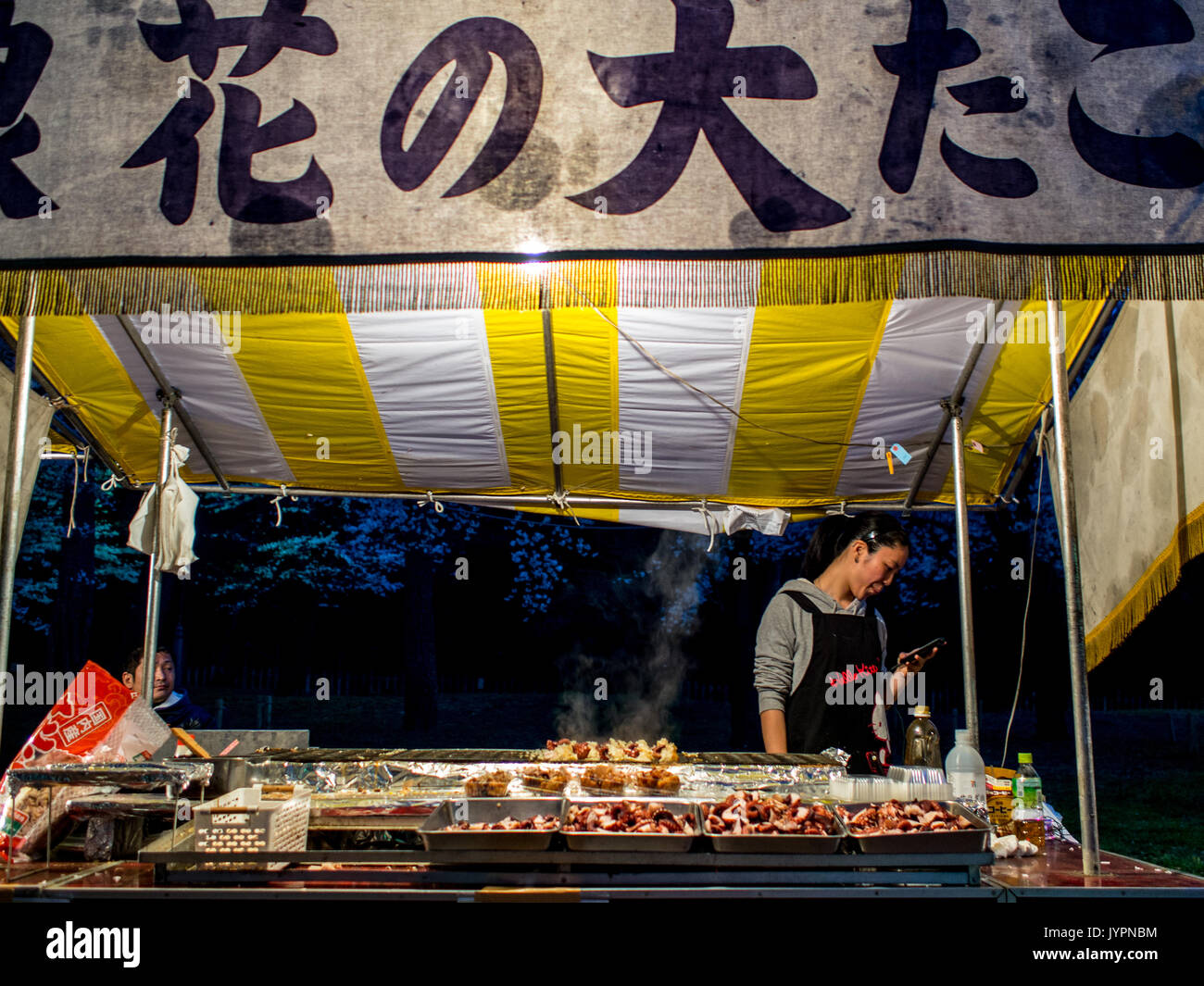 Women using mobile phone being watched by a man, takoya street food ...