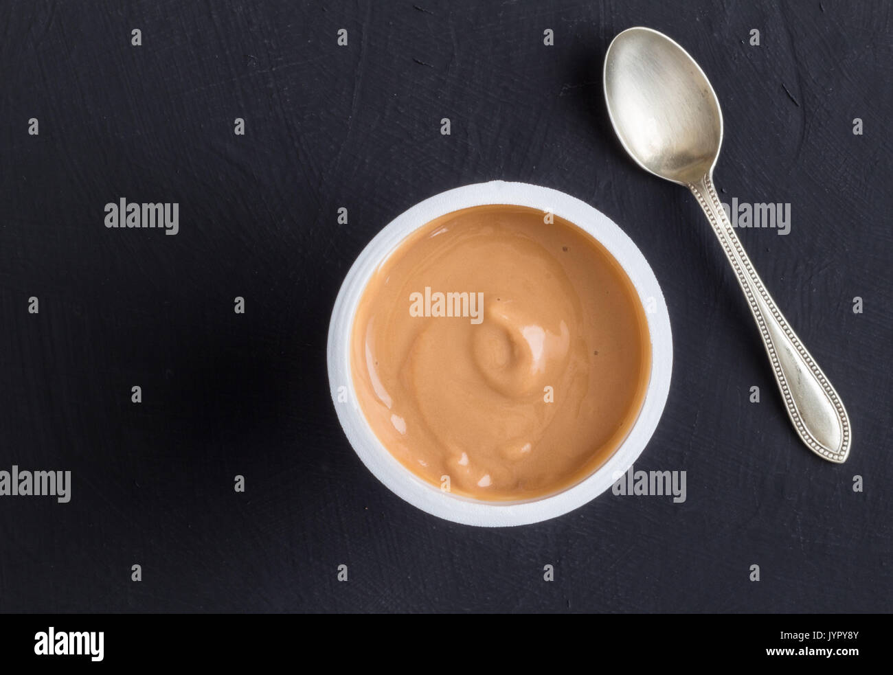 Yogurt background top view shot of caramel flavoured yoghurt in plastic ...