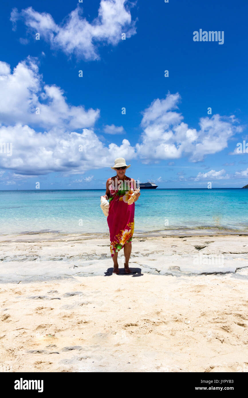 Senior woman holding conch shells on Dravuni Island beach, Fiji, South ...