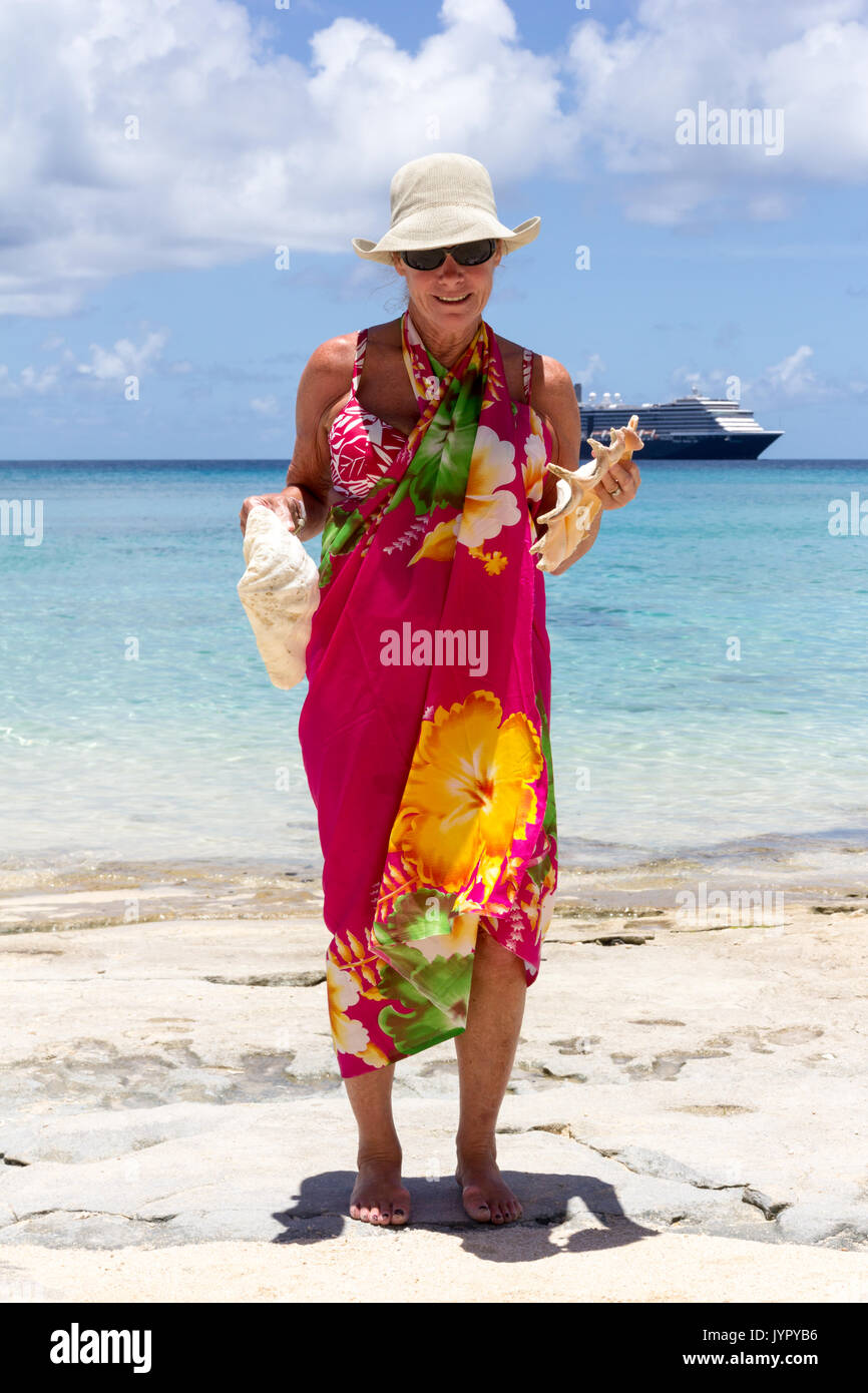 Senior woman holding conch shells on Dravuni Island beach, Fiji, South ...