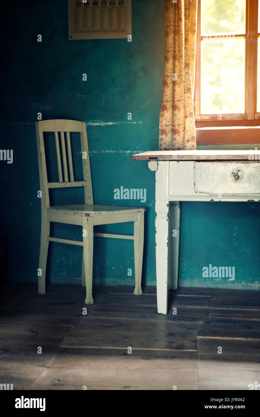 room with old vintage chair and table and sun coming through the window ...