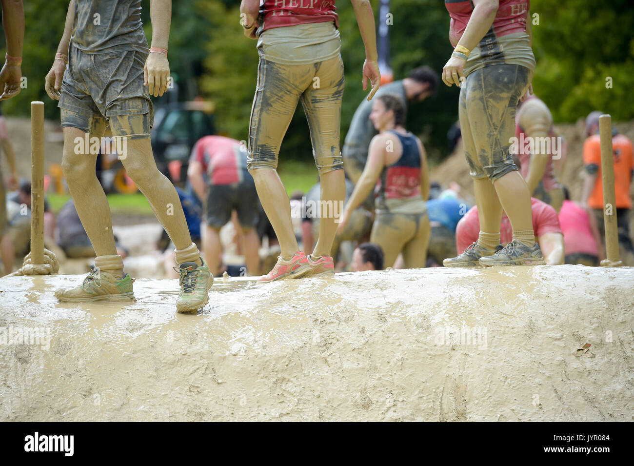 Competitors are covered in mud as they traverse the 'mud mile' obstacle ...