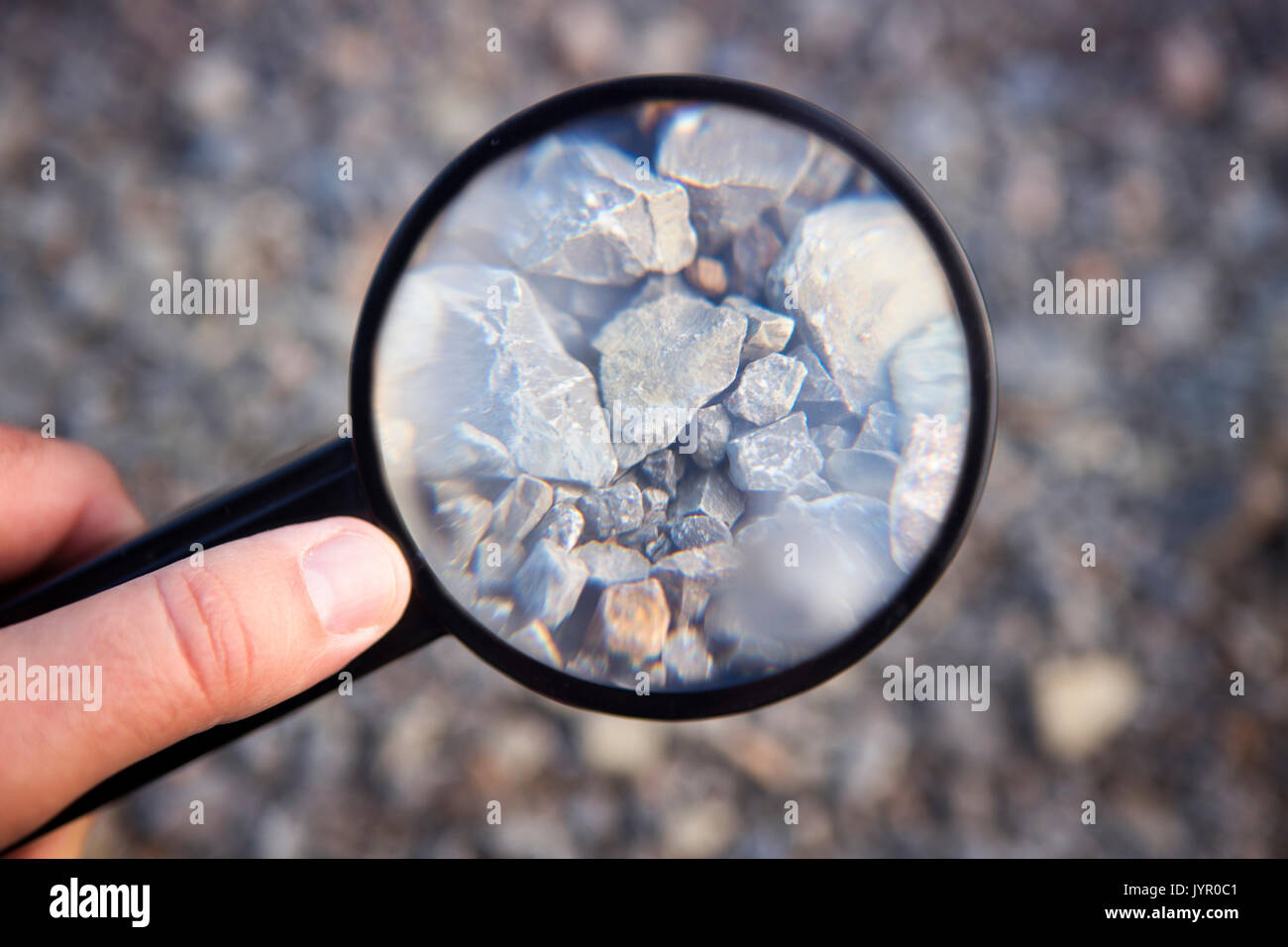 hand holding magnifying glass at grey stones Stock Photo - Alamy