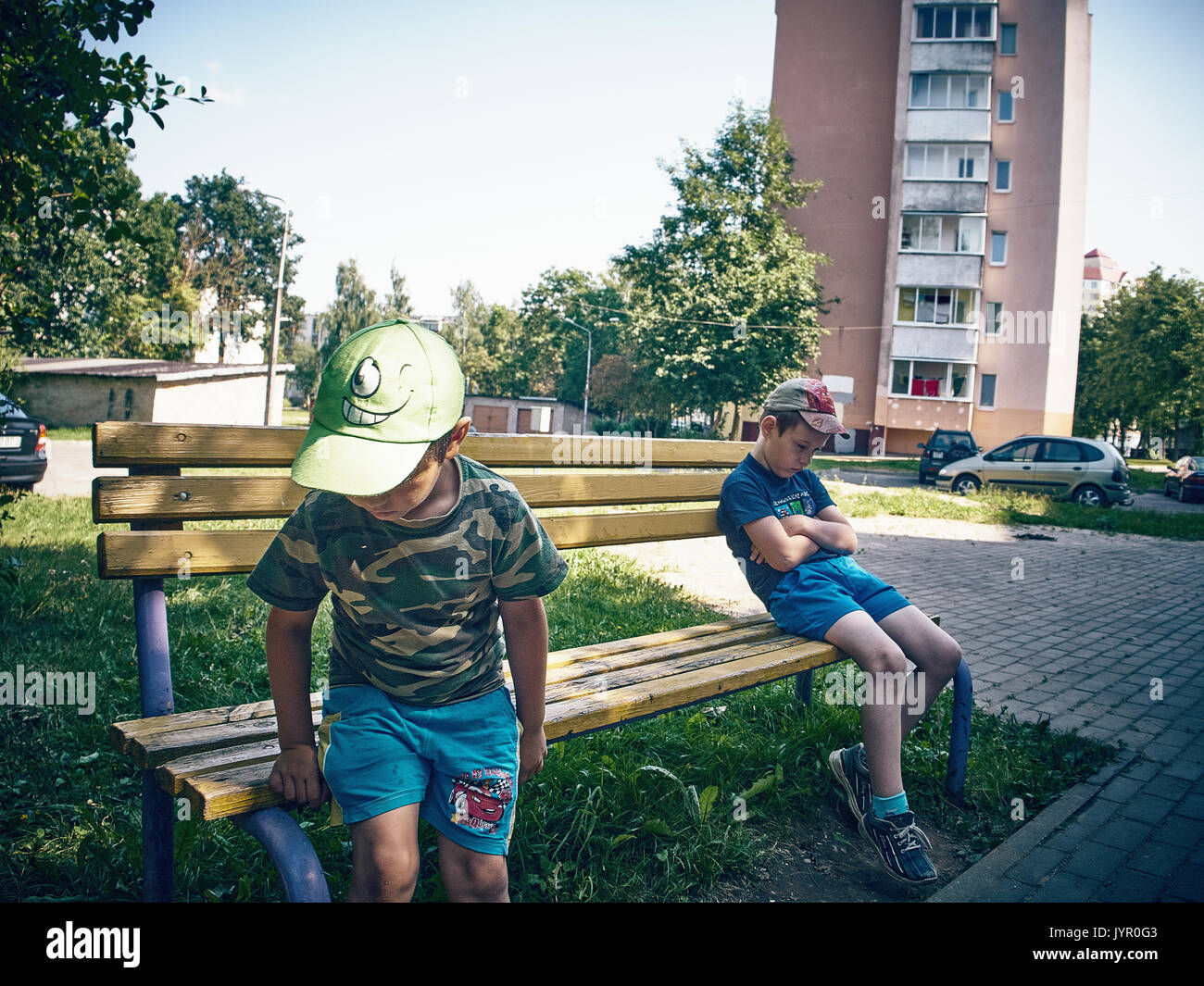 Two boys sit on opposite sides of the bench. They had a falling out and ...