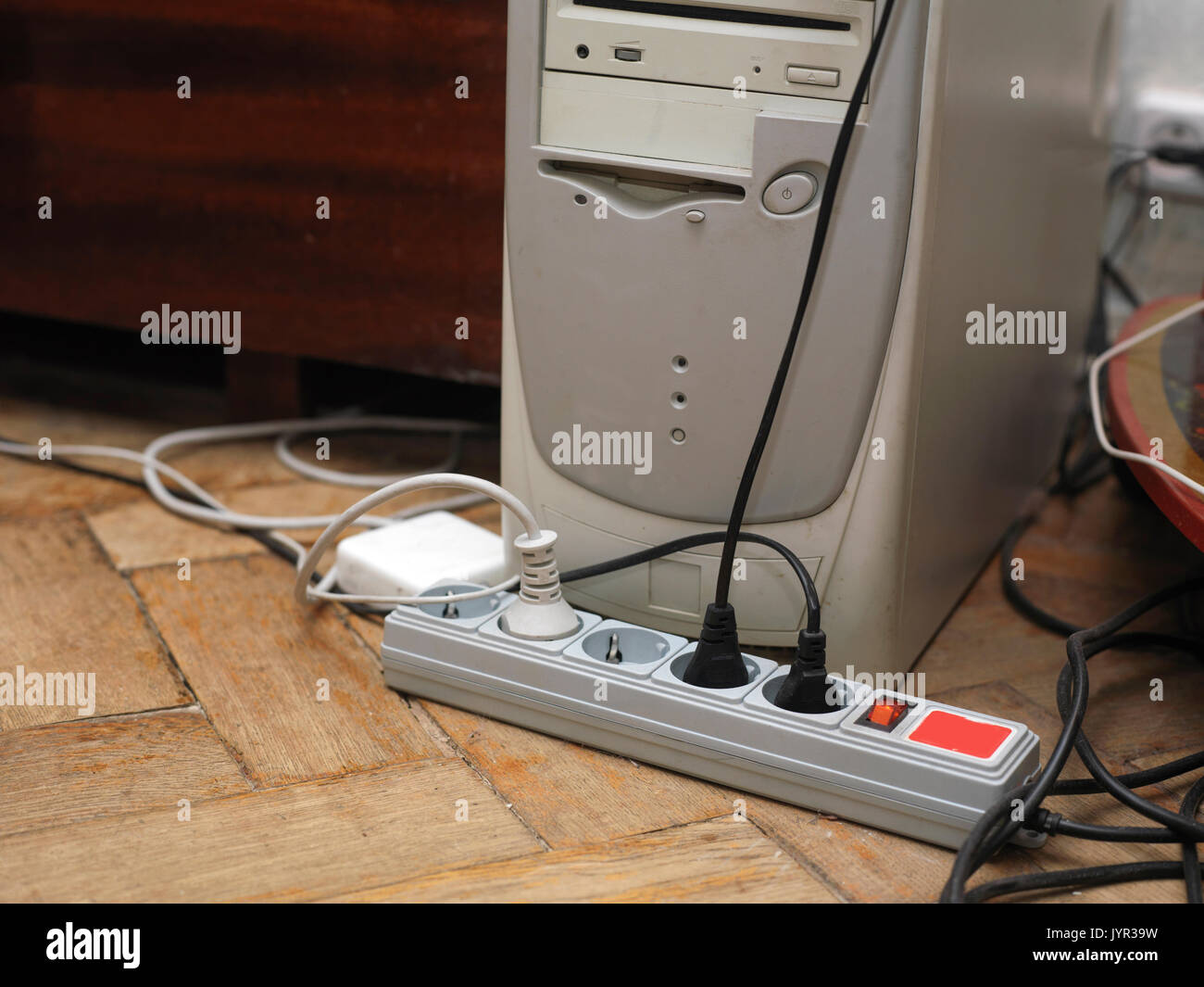 Electric extension, cables and adaptors on the wooden floor next to ...