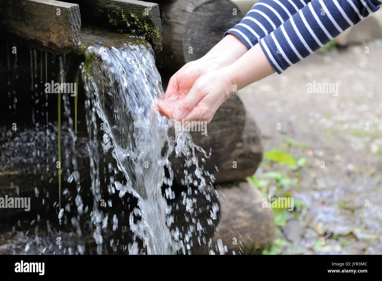 Water pouring in woman hand on nature background Stock Photo - Alamy