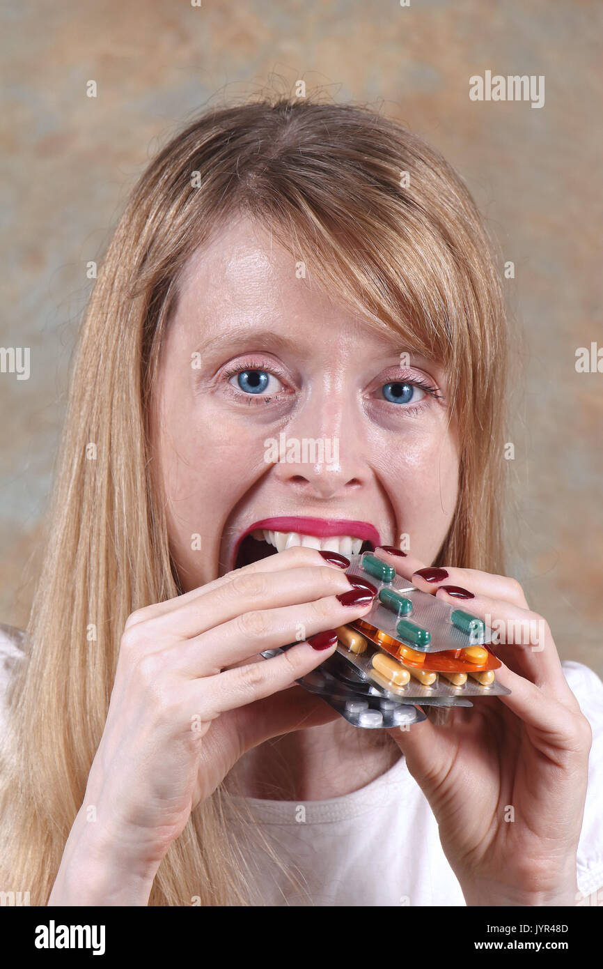 Young blonde woman eating prescription pills blisters Stock Photo - Alamy