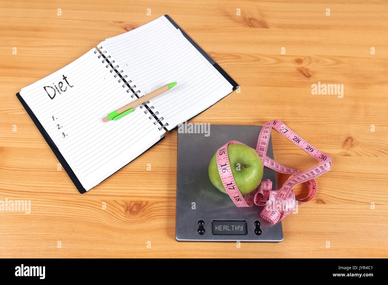 Open diet plan notebook and scale with green apple and tape measure ...