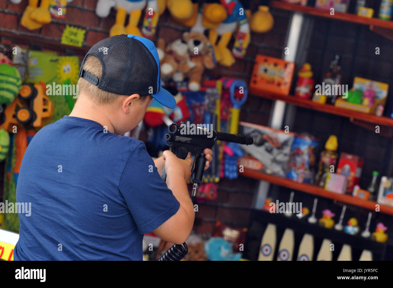 A young man holding and shooting a gun or rifle that fires corks at a ...