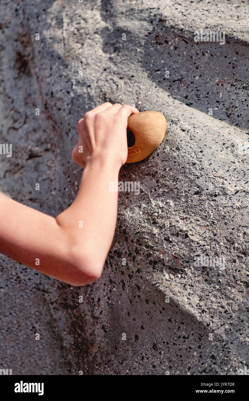 Closeup of a hand gripping a hold on a rock wall with sharp focus on ...