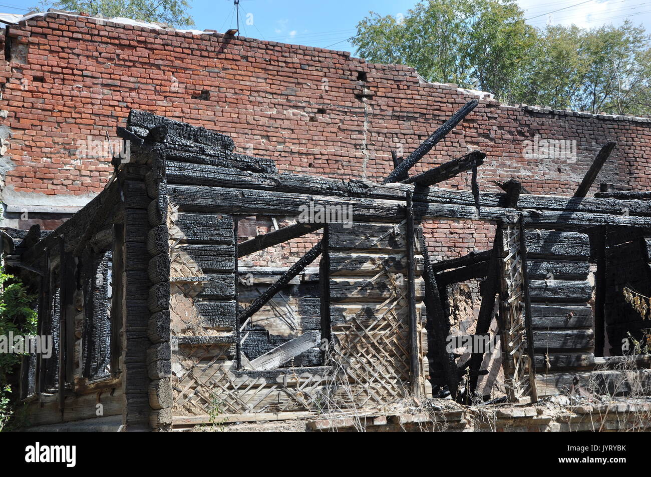 Charry corner of a burnt house with ruined wooden framework against a ...