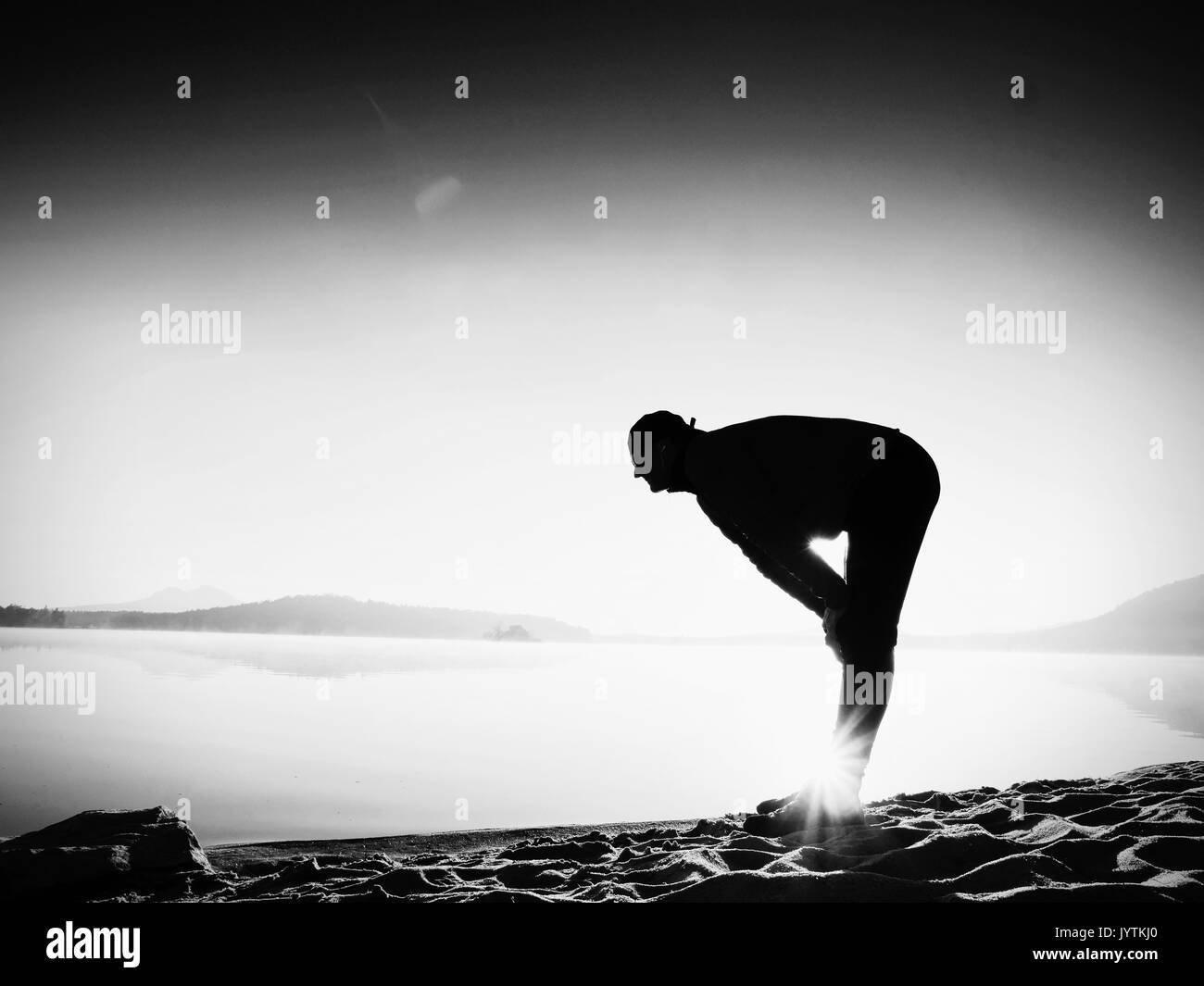 Deep breathing runner silhouette bended with hands on knees. Side view ...