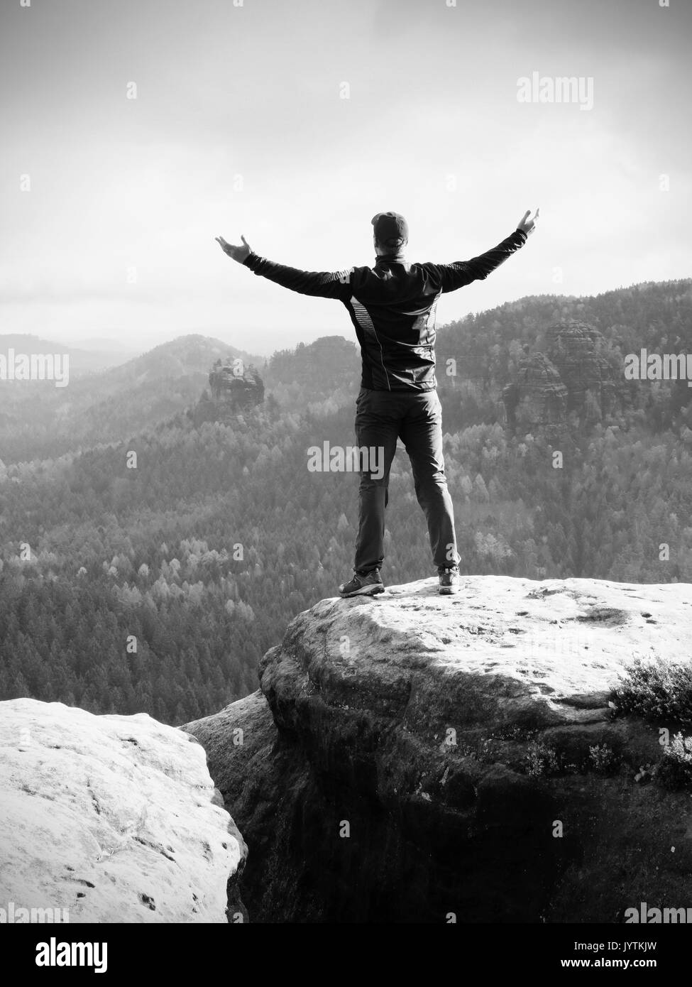 Alone hiker in red cap stand on the peak of sandstone rock in rock ...