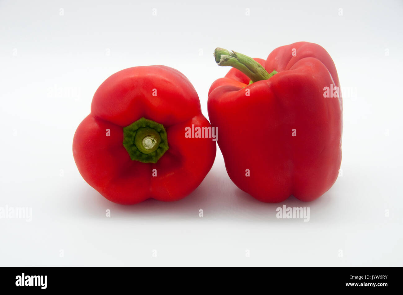 A simple photograph of two red bell peppers, one on its side, one ...