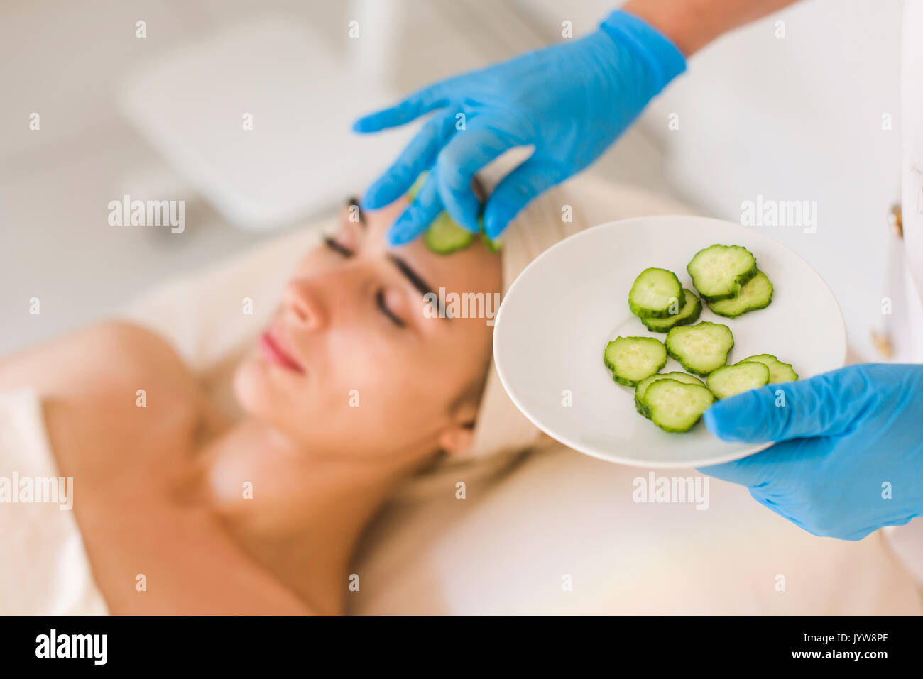 Young woman with facial mask of cucumber in beauty salon. Cosmetic mask ...