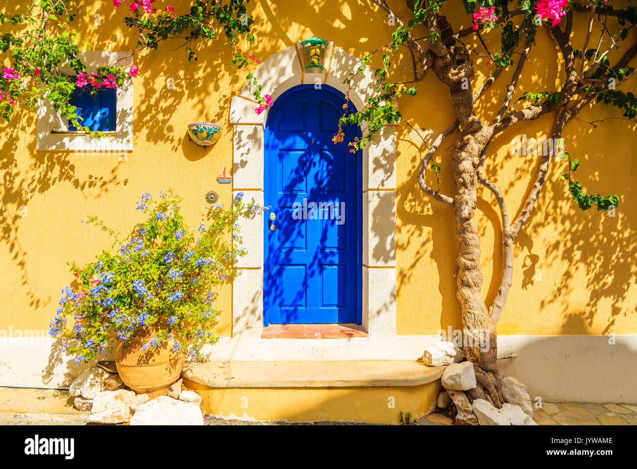 Blue door of a yellow Greek house decorated with flowers, Assos town ...