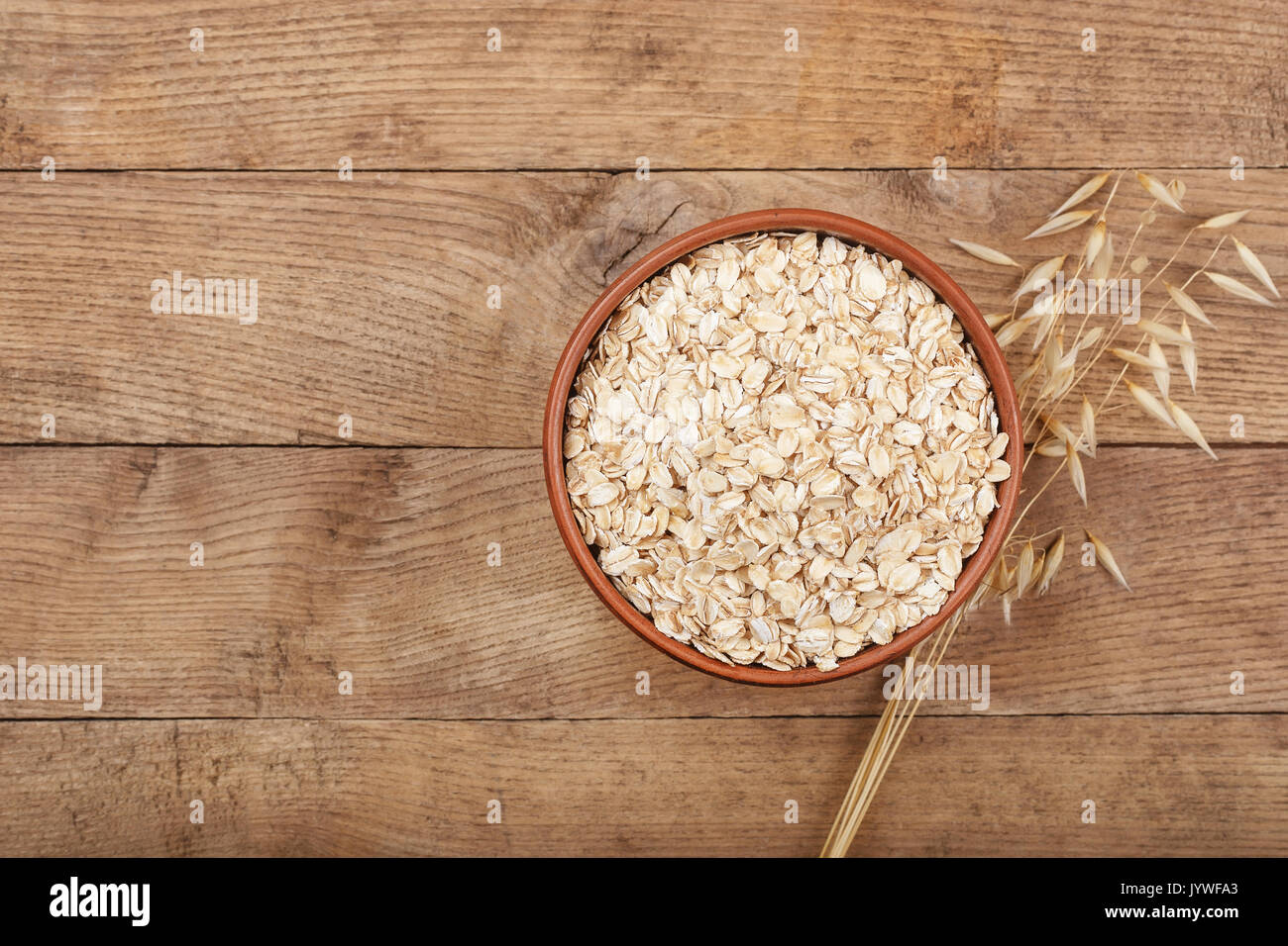 oat flakes in bowl and oat ear on wooden table top view. Uncooked ...