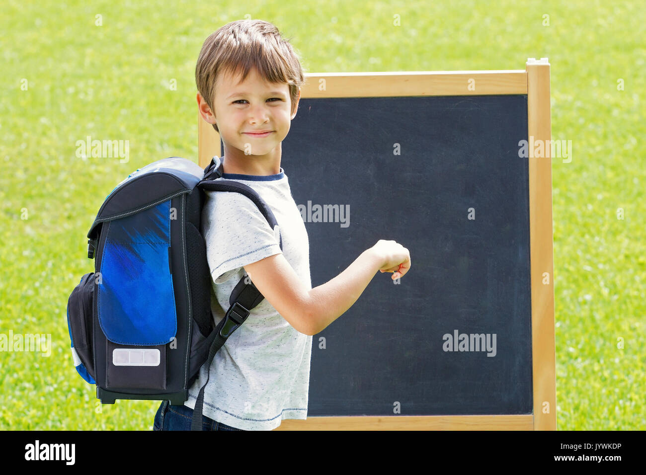 Cute little boy with backpack at small blackboard outdoor Stock Photo ...