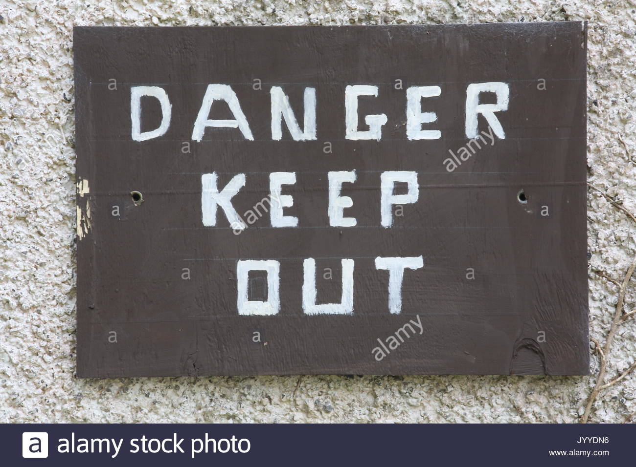 A Danger Keep Out sign written in white block letters sign on a wall ...