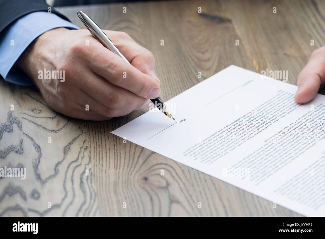 Business man signing a contract with shallow focus on pen and date ...