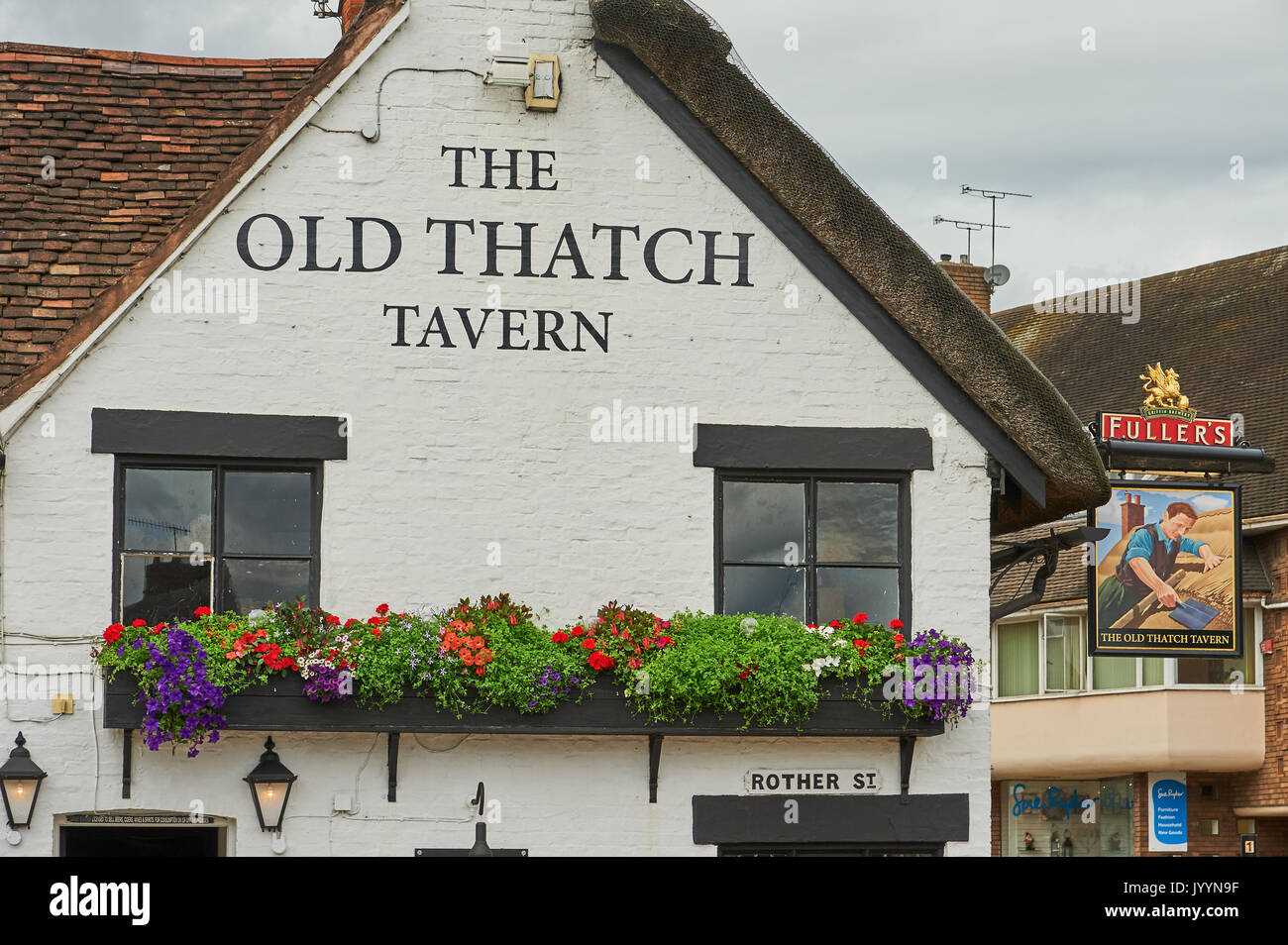The Old Thatch Tavern public house with colourful hanging baskets in ...