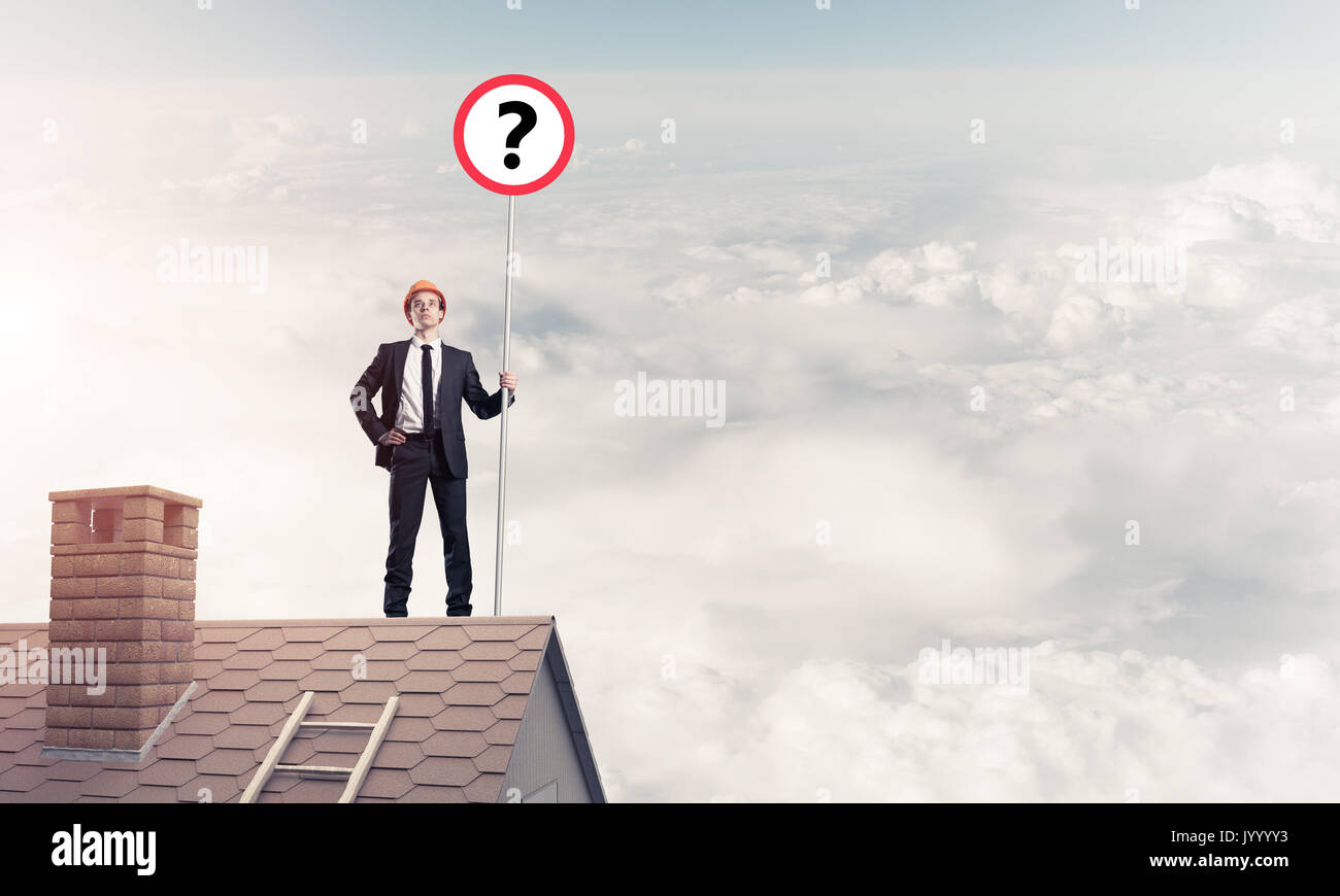 Businessman on brick house roof showing banner with question mar Stock ...