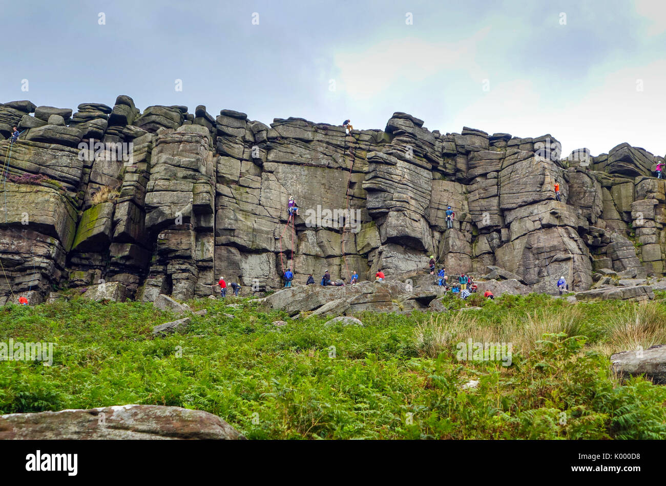 Rock climbers in bright colours on Stanage Edge, Peak District ...