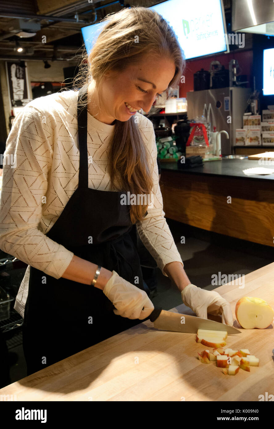 Woman, wearing gloves, slices apples on a cutting board in an ...